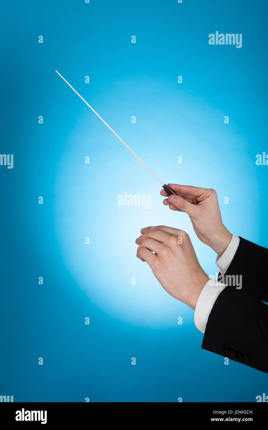Cropped image of musician holding baton against blue background Stock ...