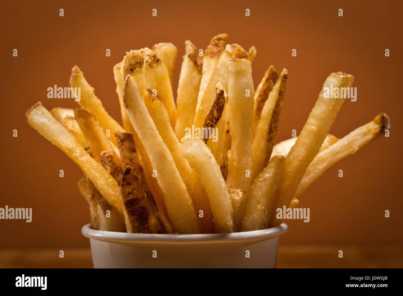 Cup of french fries on brown background Stock Photo - Alamy