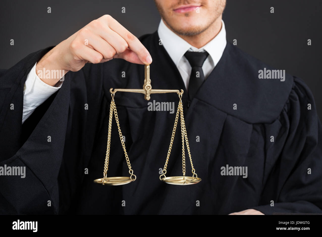 Midsection of male judge holding weight scale against black background ...