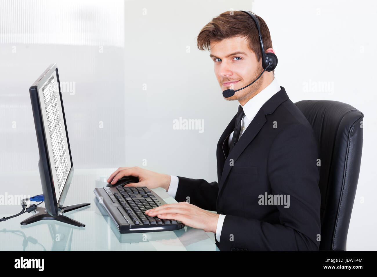 Side view of confident businessman in headset using computer at office ...