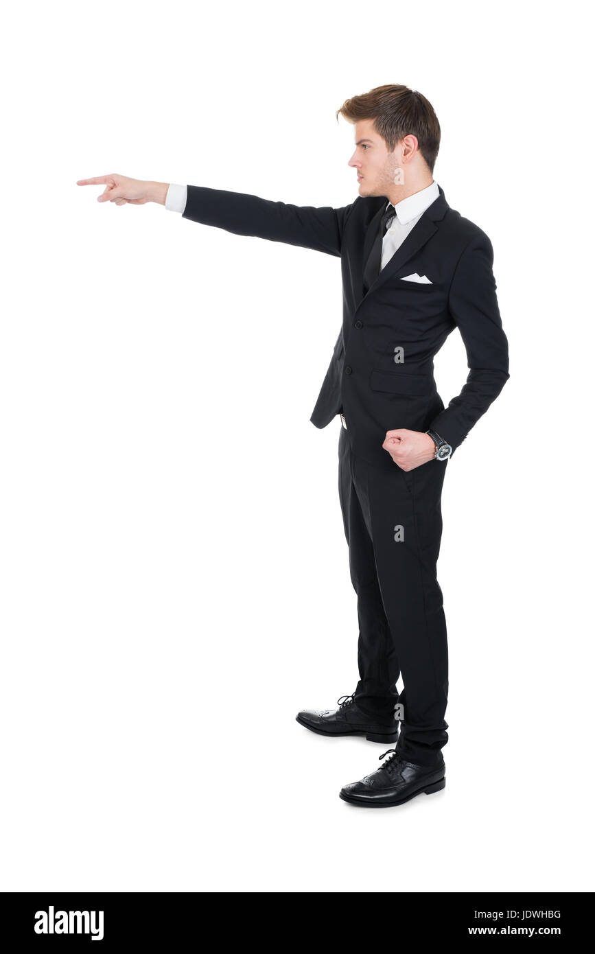 Full length side view of angry businessman pointing against white ...