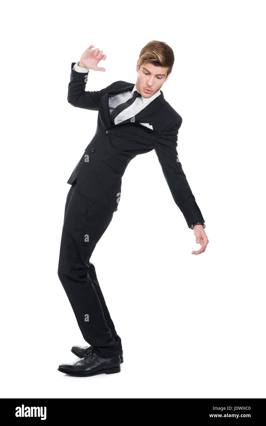 Full length of scared young businessman about to fall over white ...