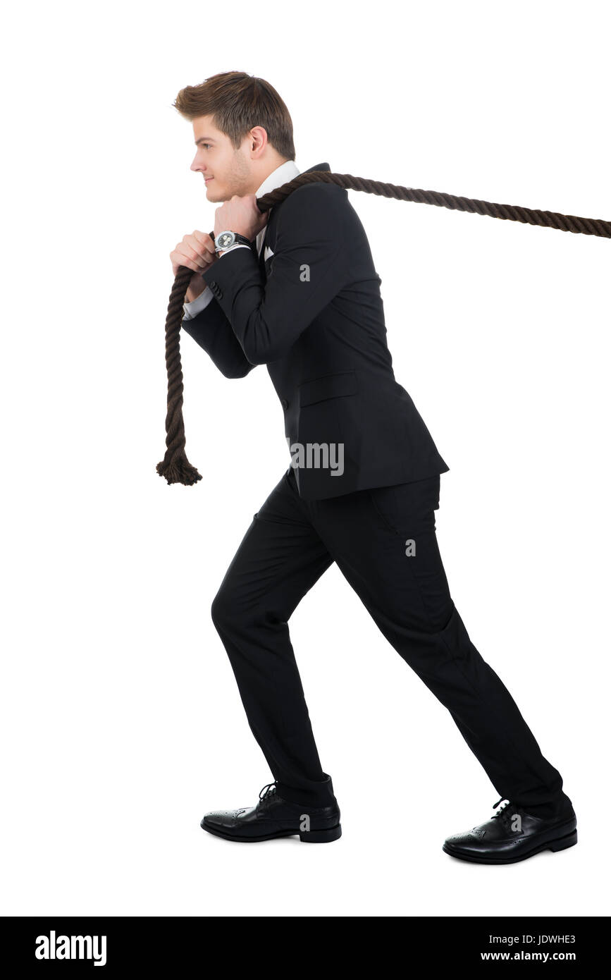 Full length side view of businessman pulling rope against white ...
