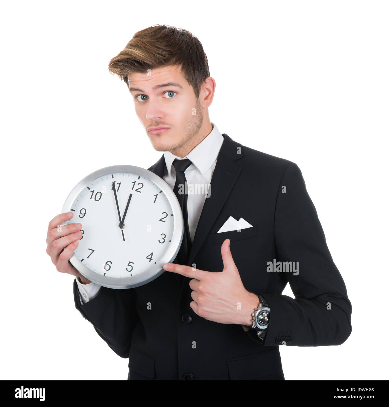Portrait of young businessman pointing at clock against white ...