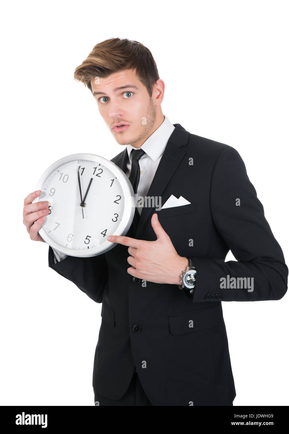 Portrait of young businessman pointing at clock against white ...