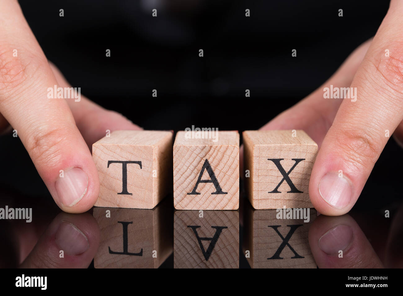 Cropped image of businessman holding Tax blocks on desk Stock Photo - Alamy