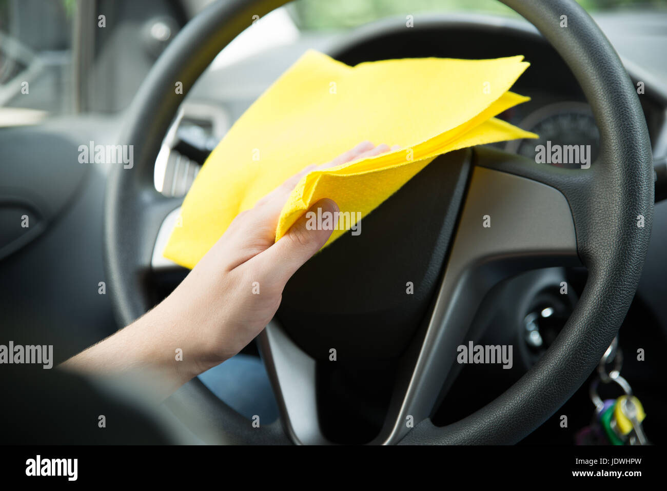 Man's hand cleaning steering wheel of car with yellow microfiber cloth ...