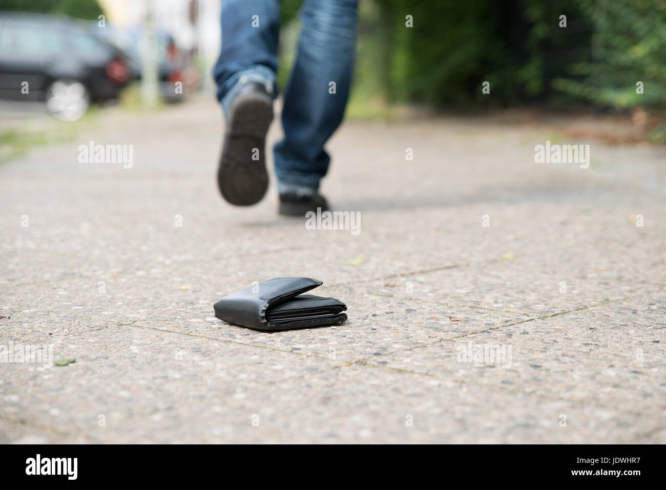 Low section of man walking against fallen wallet on street Stock Photo ...
