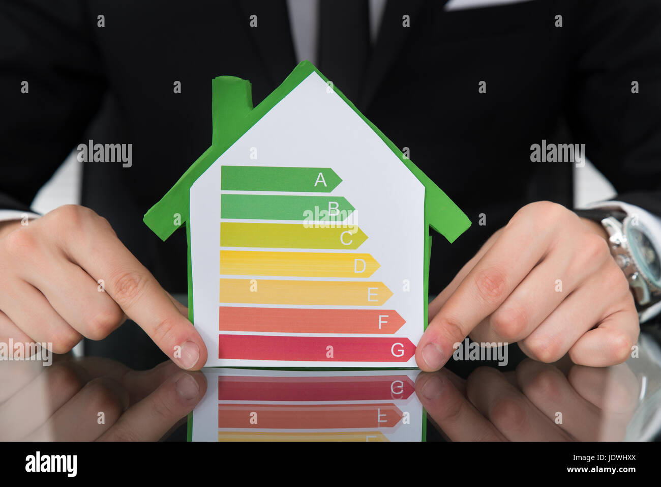 Cropped image of businessman showing energy efficient chart on house ...