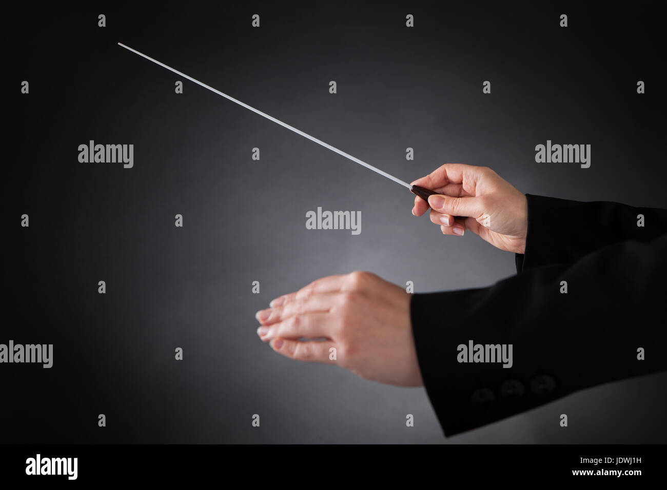 Close-up Of Female Orchestra Conductor Holding Baton Over Black ...