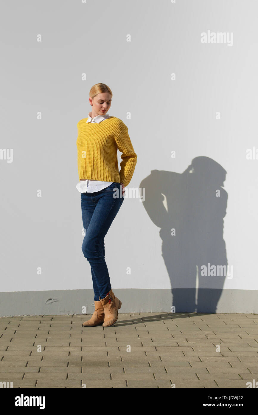Girl posing in front of the wall with funny shadow on it. Streetstyle ...
