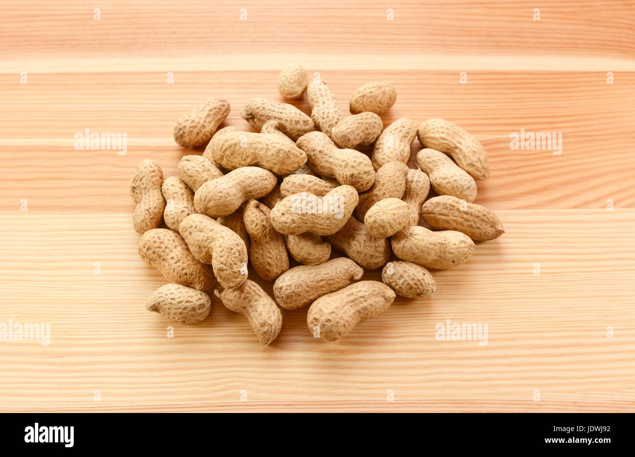 Heap of monkey nuts, peanuts or groundnuts in shells on a wood grain ...