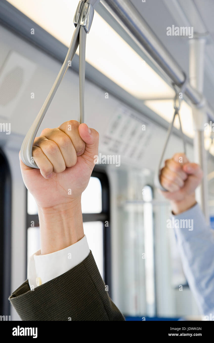 People holding handles on train Stock Photo - Alamy