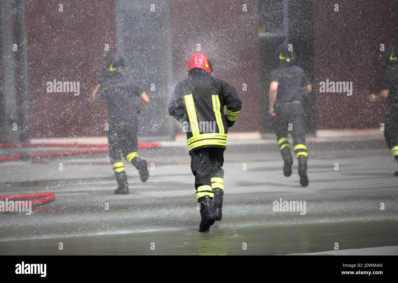 Firefighters run fast under the splashes of water Stock Photo - Alamy