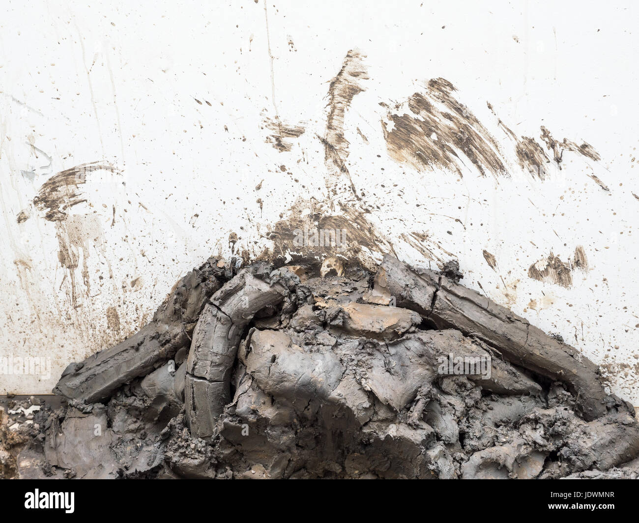 Clay pile from the construction site near the white concrete wall of ...