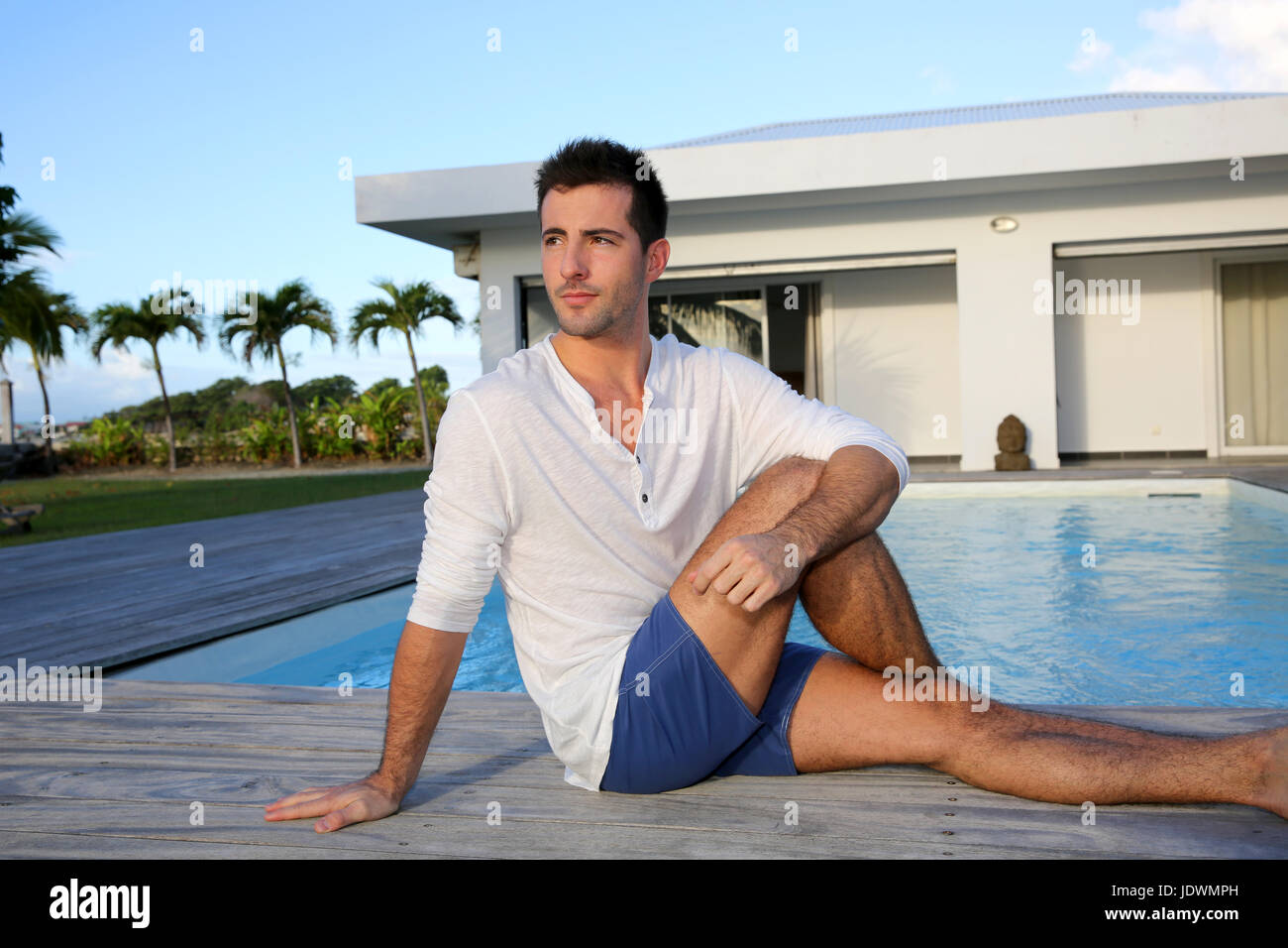 Young man doing stretching exercises on pool deck Stock Photo - Alamy