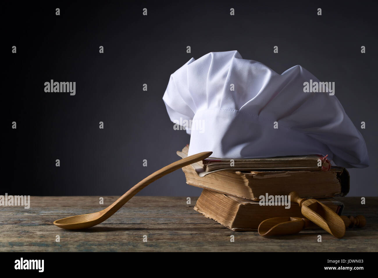 Old culinary books , chef hat and wooden spoons . Kitchen accessories ...