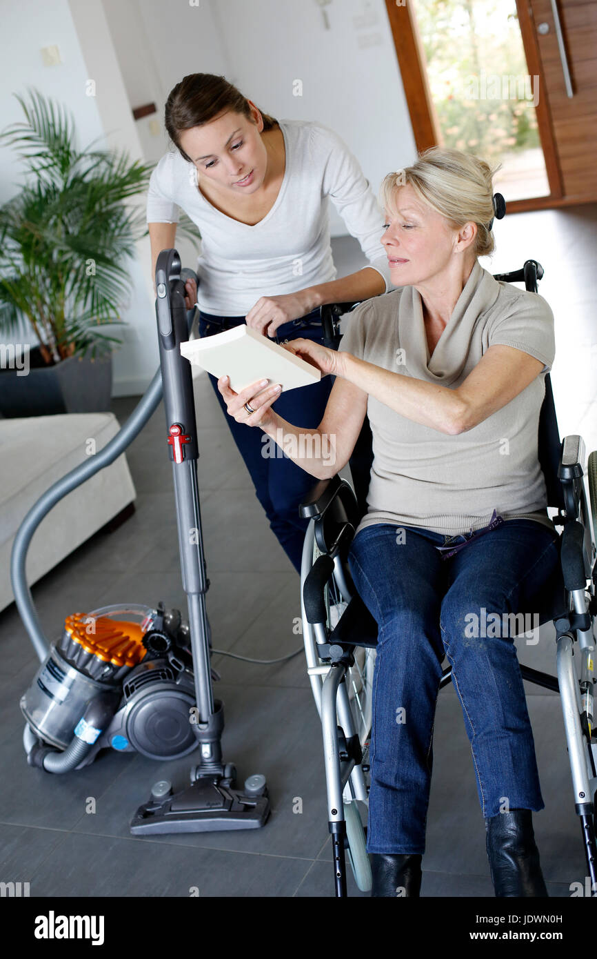 Young woman helping disabled lady at home Stock Photo - Alamy