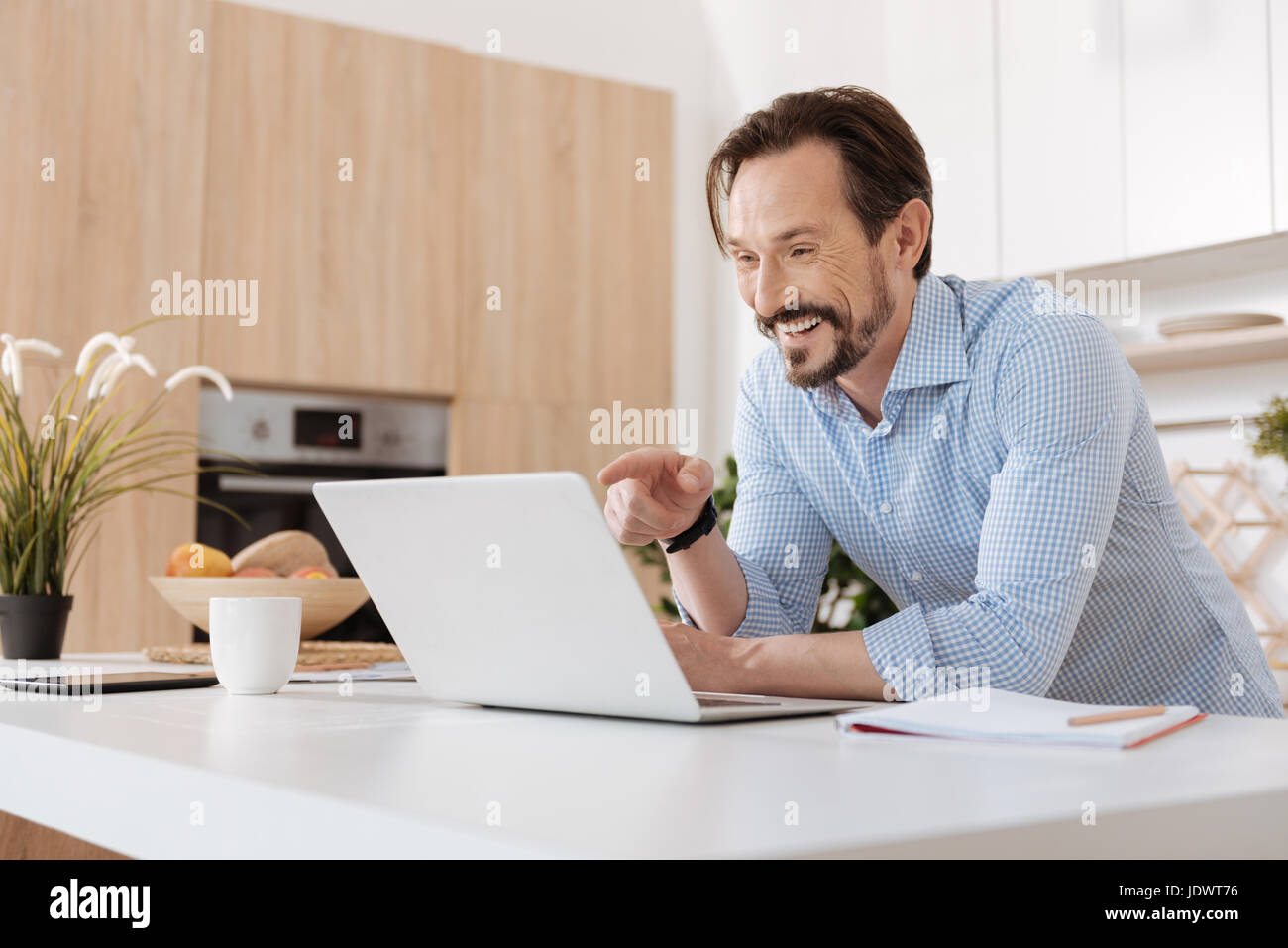 Cheerful man laughing while looking at the laptop Stock Photo - Alamy