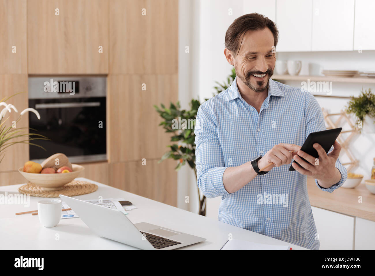Joyful young man reading something on the tablet Stock Photo - Alamy
