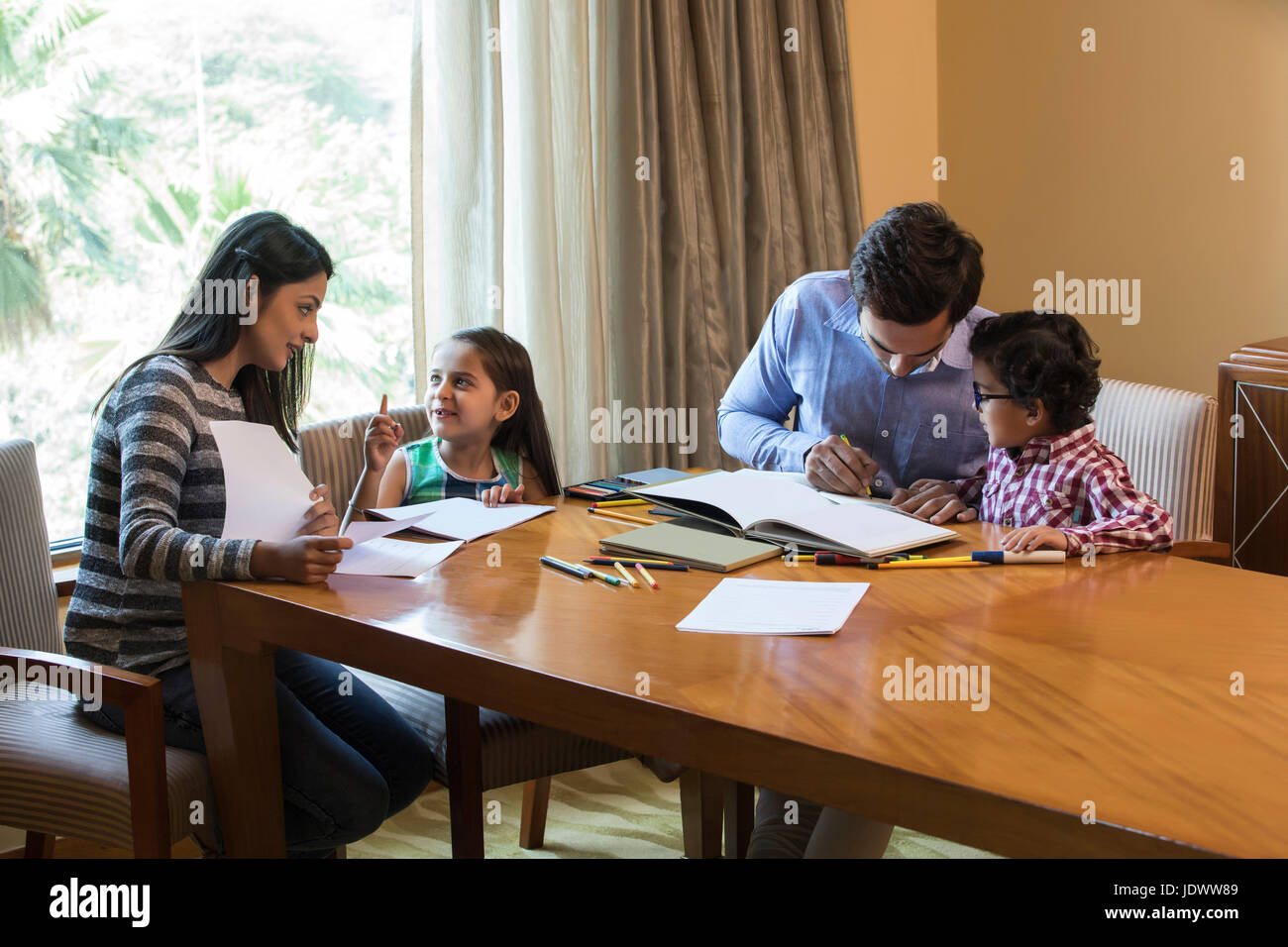Mother and father helping daughters with homework Stock Photo - Alamy