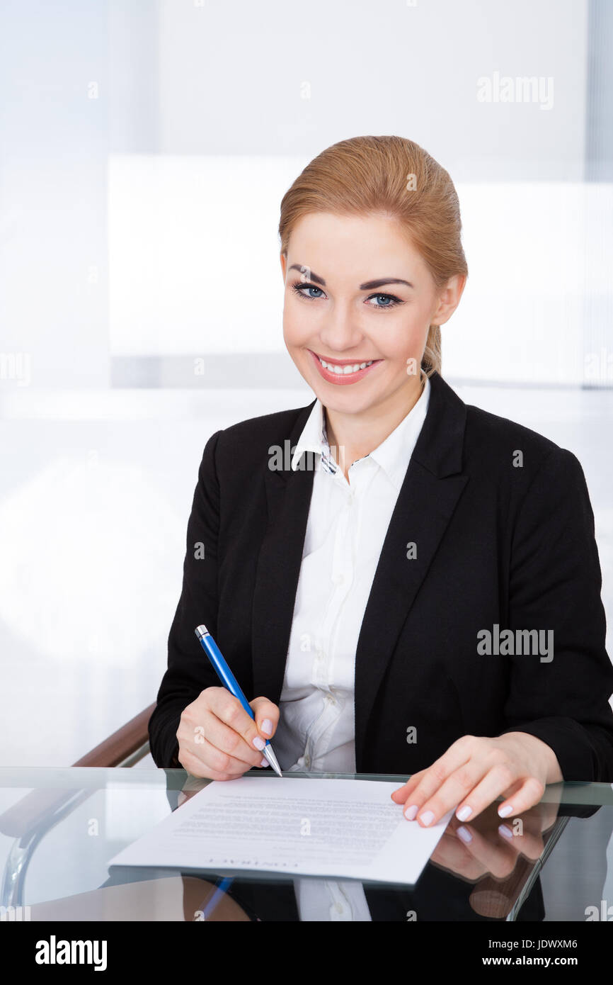 Portrait Of A Young Businesswoman At Desk Signing Document Stock Photo ...
