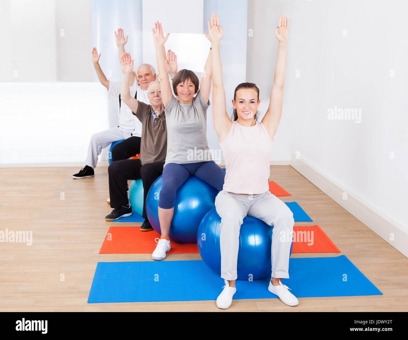 Full length portrait of trainer and senior customers stretching on ...
