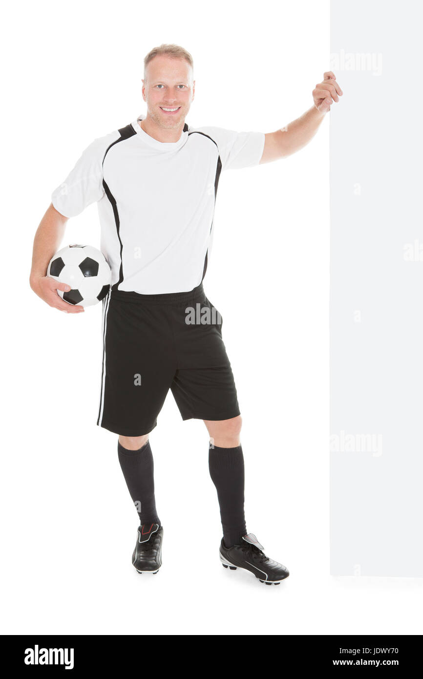 Full length portrait of young soccer player with football pointing at ...