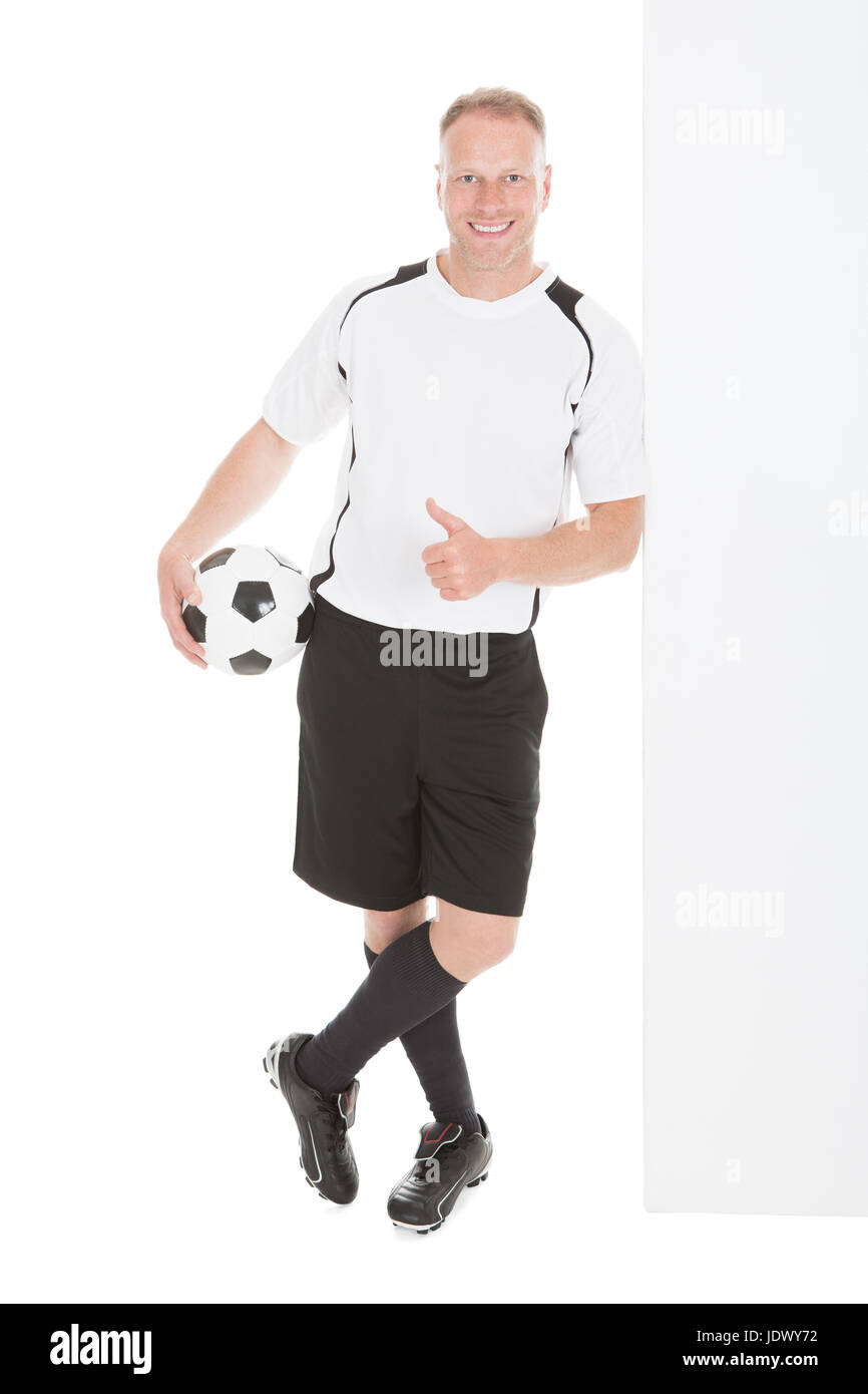 Full length portrait of young soccer player with football pointing at ...