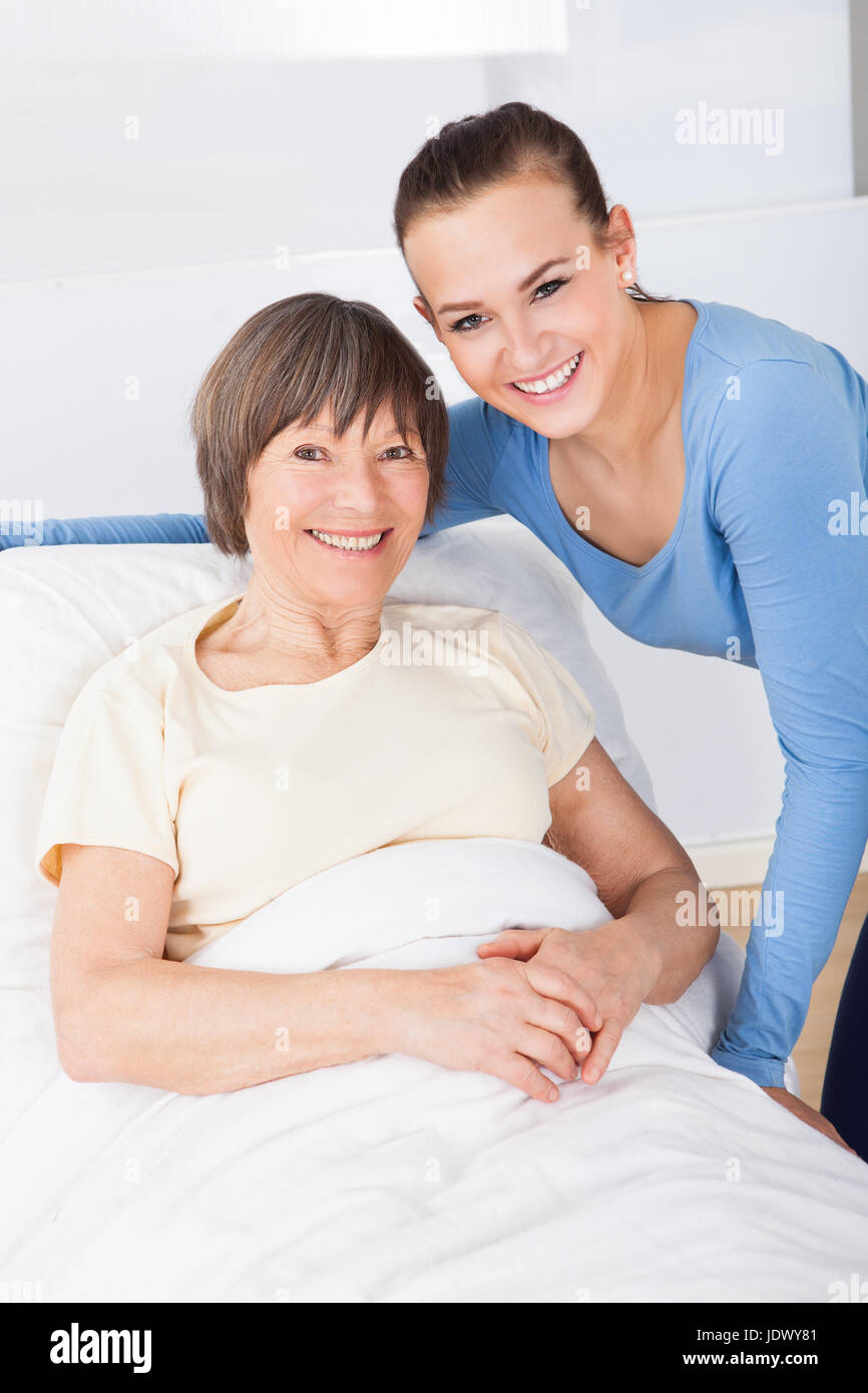Portrait of happy young female caregiver with senior woman in nursing ...