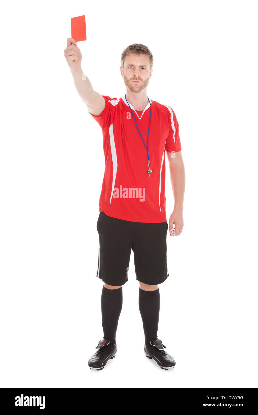 Full length portrait of referee showing red card over white background ...