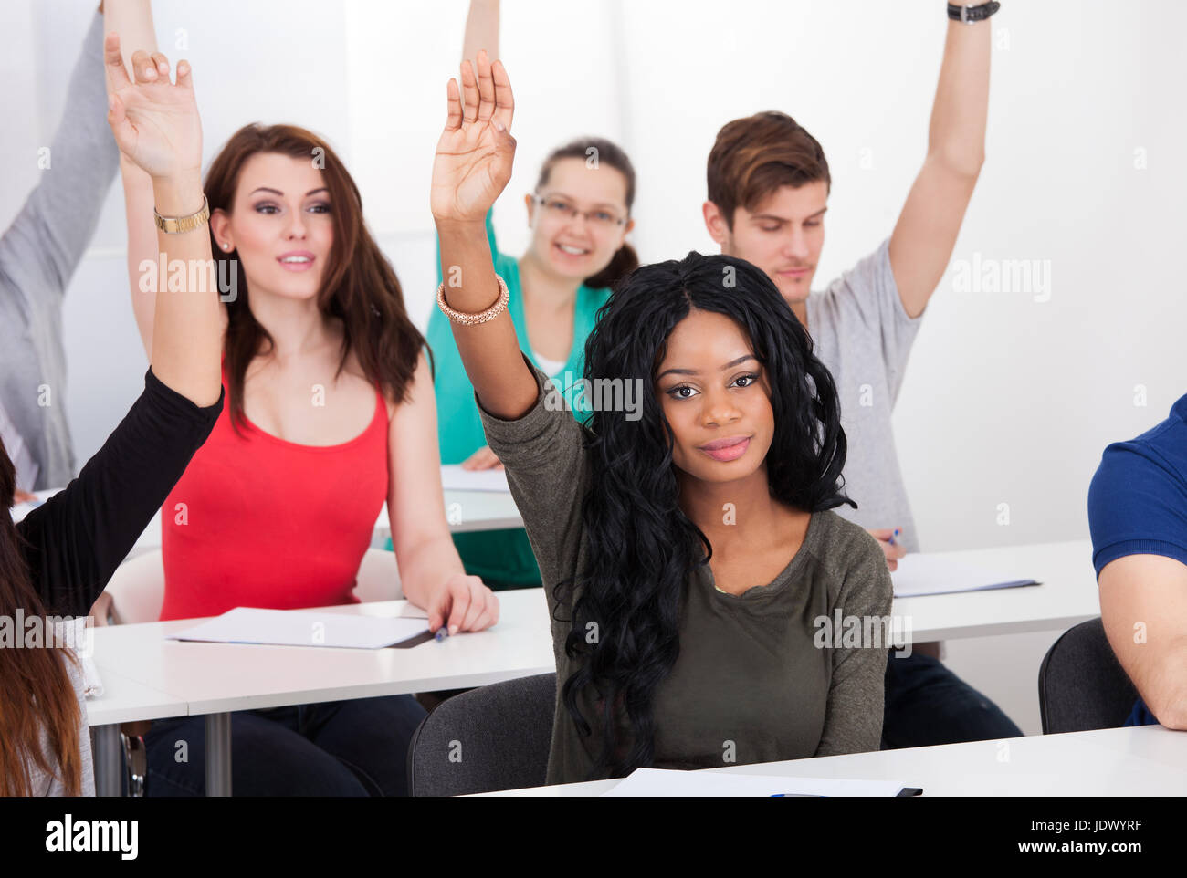 Portrait of female college student answering question with raised hand ...