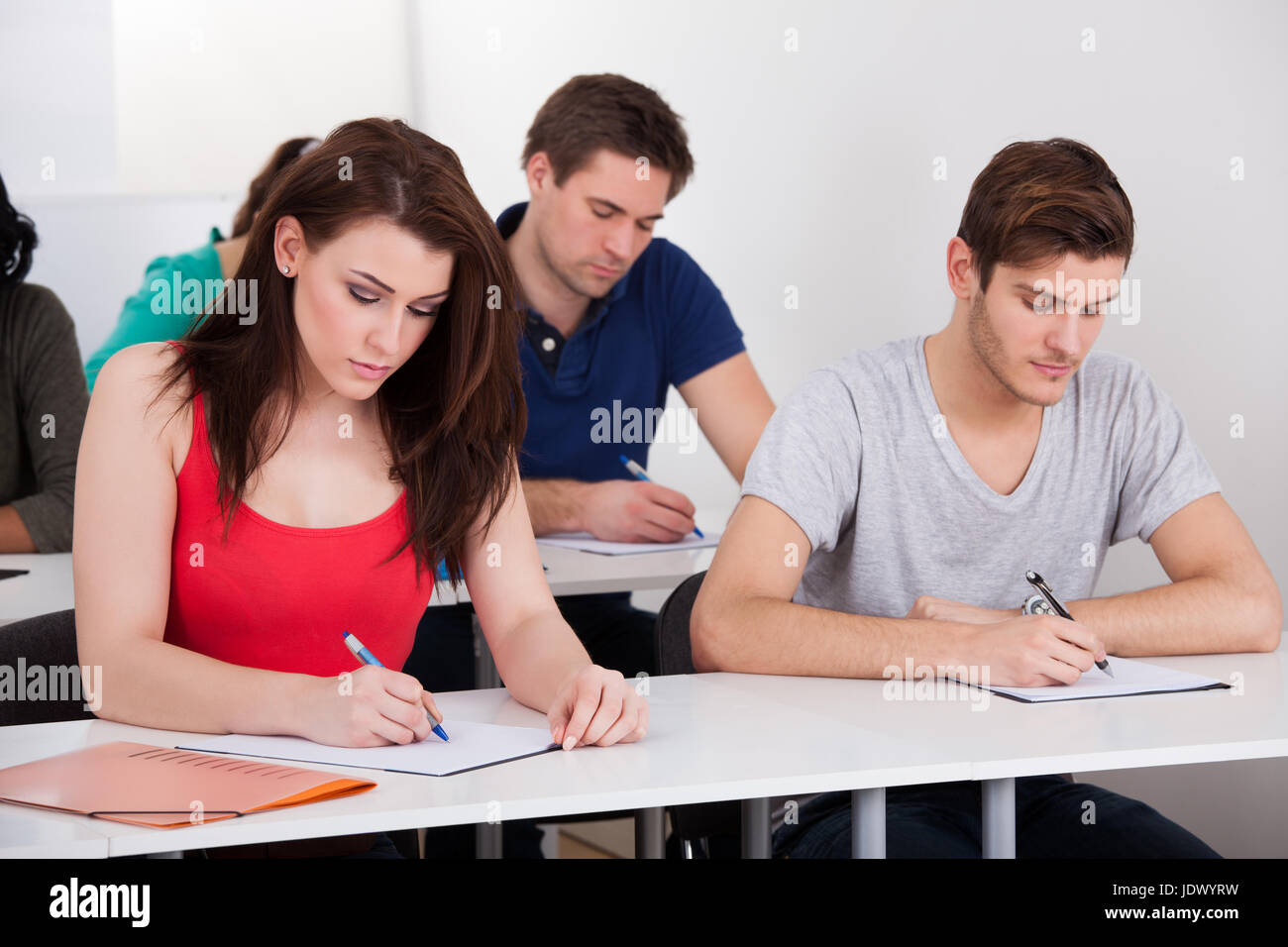 Young college students writing at desk in classroom Stock Photo - Alamy