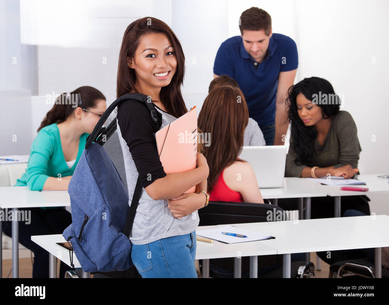 Portrait of smiling female college student carrying backpack with ...
