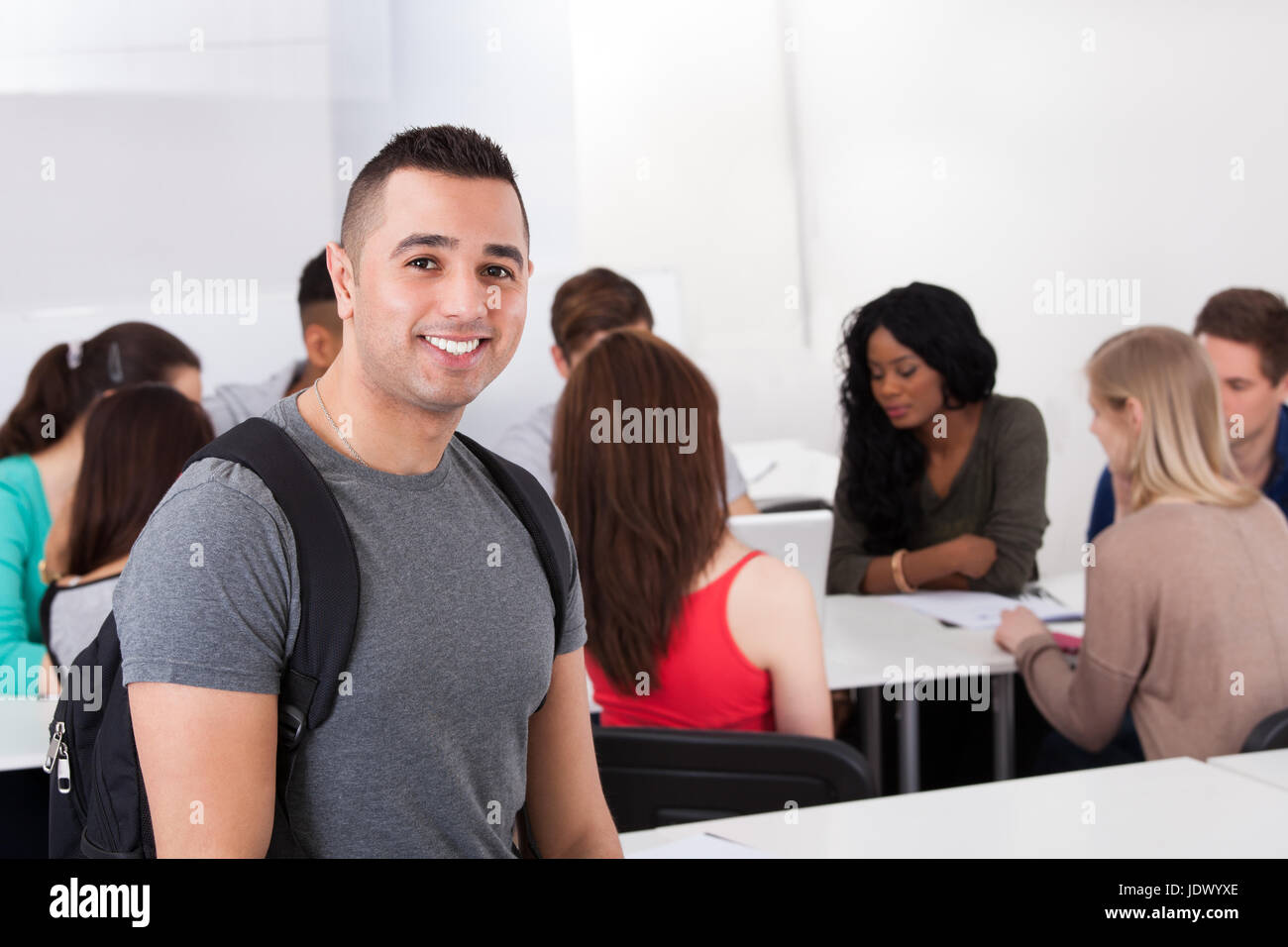Portrait of confident male college student carrying backpack with ...