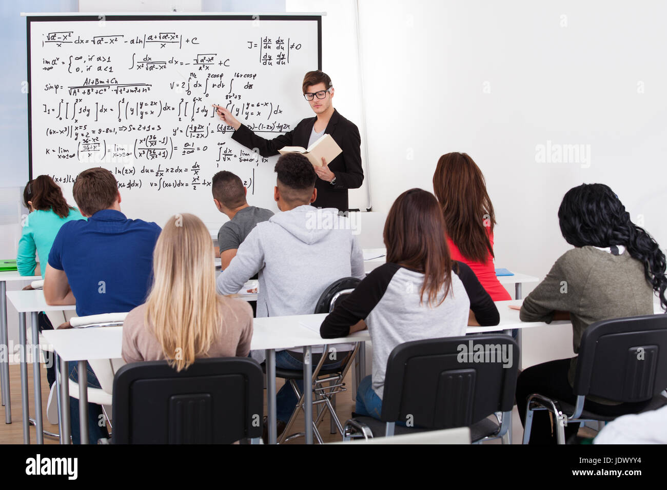 Young teacher teaching math formulas to college students in classroom ...