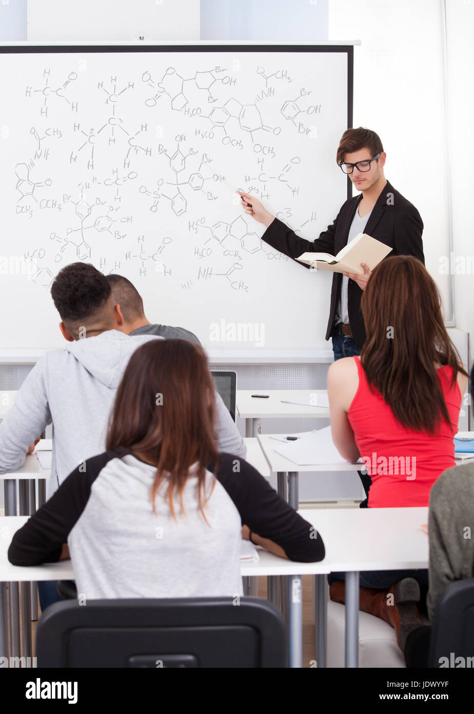 Young teacher teaching chemical formulas to college students in ...