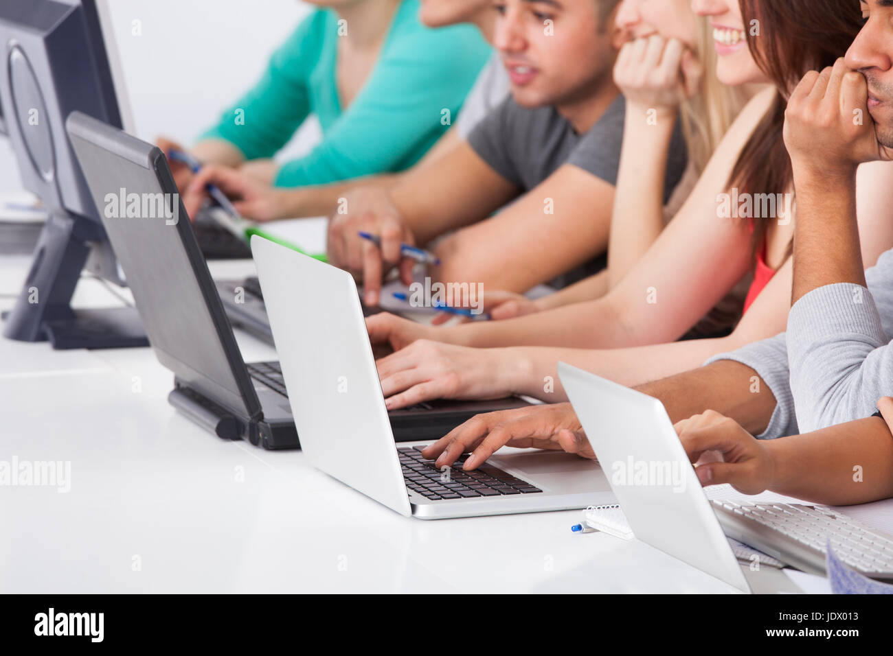 Cropped image of college students using laptops at desk Stock Photo - Alamy