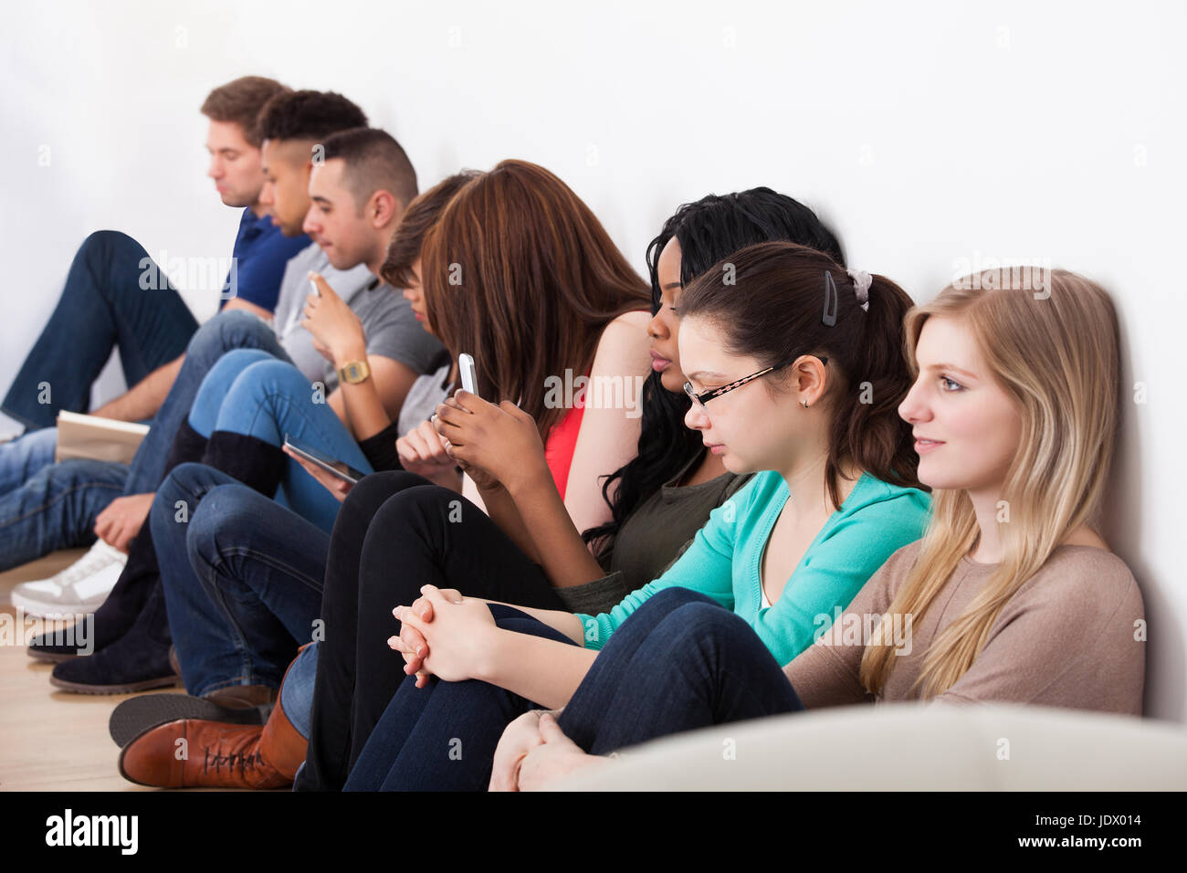 Multiethnic college students sitting against wall in classroom Stock ...