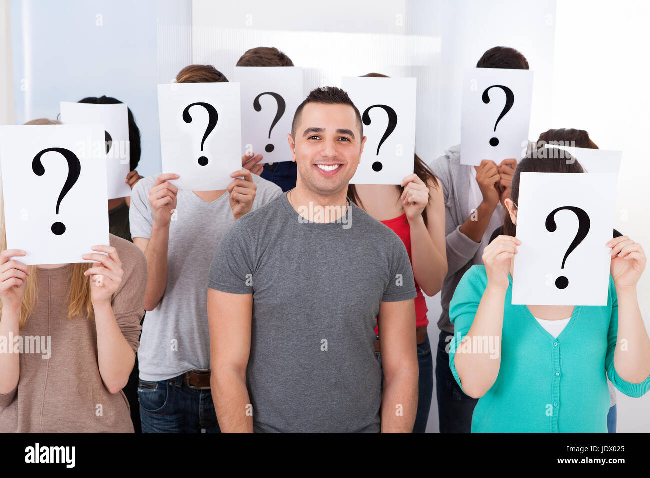 Portrait of confident college student surrounded by classmates holding ...
