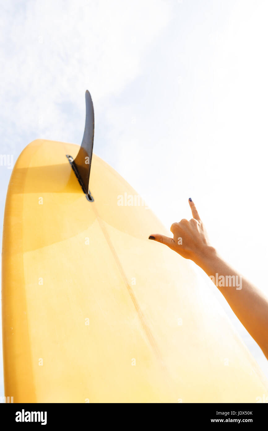 Close up of a woman hand show surfing sign shaka in front of yellow ...