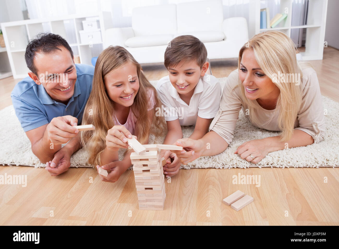 Happy Family Laying On Carpet Playing With The Wooden Blocks At Home ...