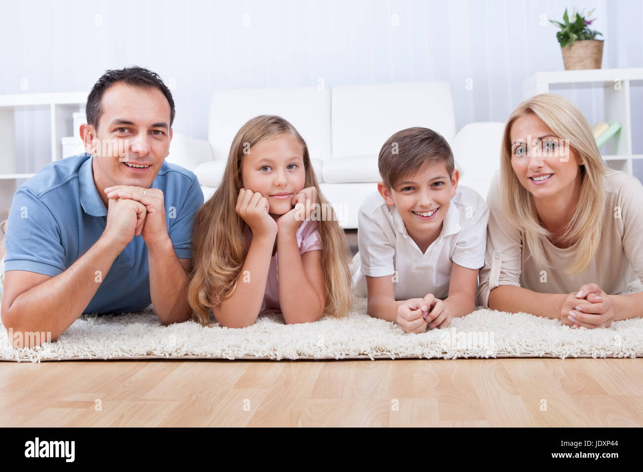 Portrait Of Happy Family With Two Children Laying On Carpet At Home ...