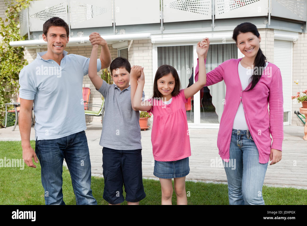 Happy family standing together holding hands outside their home Stock ...