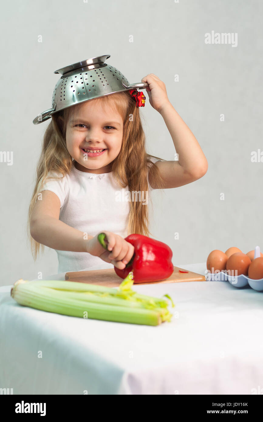 Girl playing in a cook. Carried away by the game she put on a colander ...
