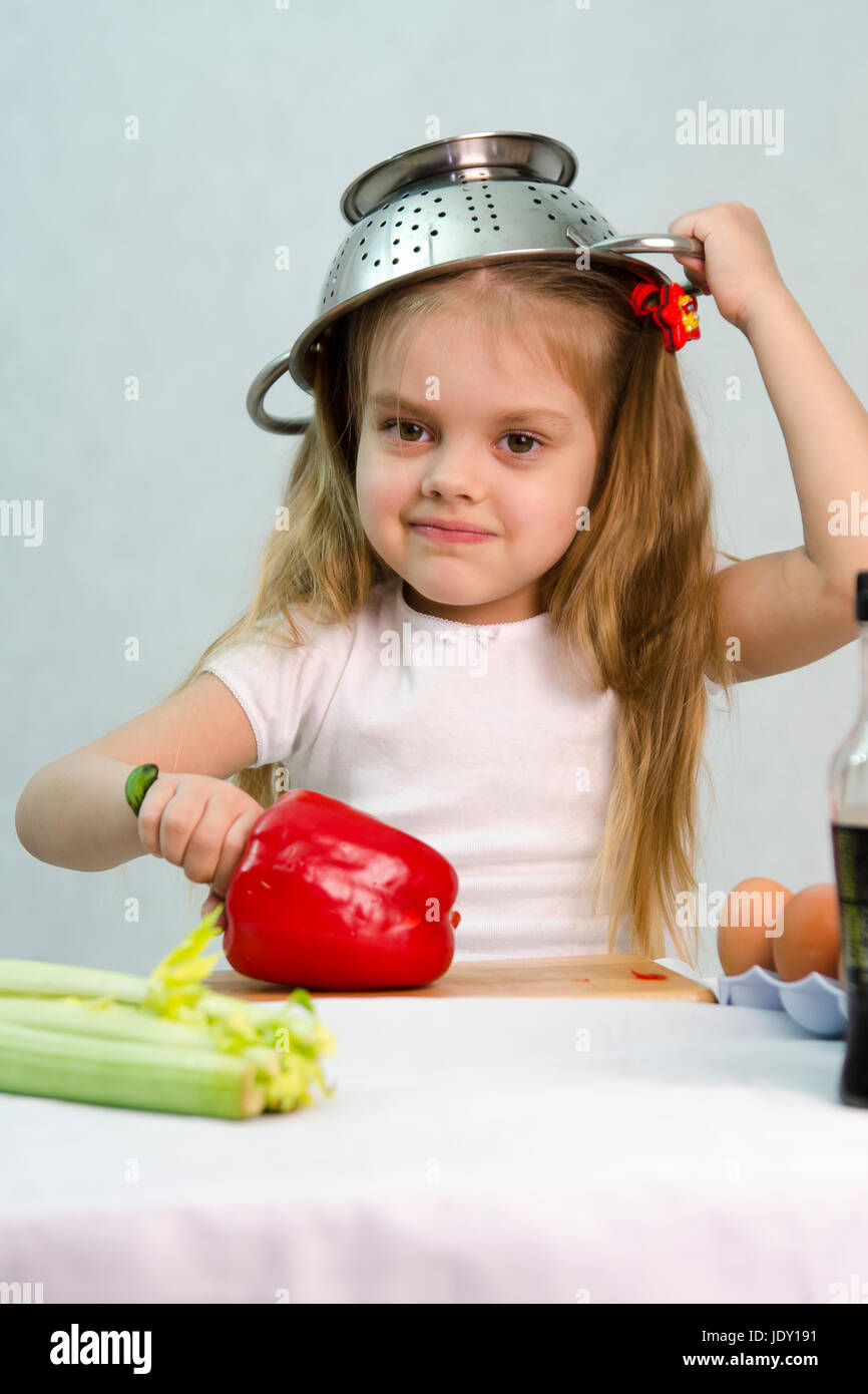 Girl playing in a cook. Carried away by the game she put on a colander ...