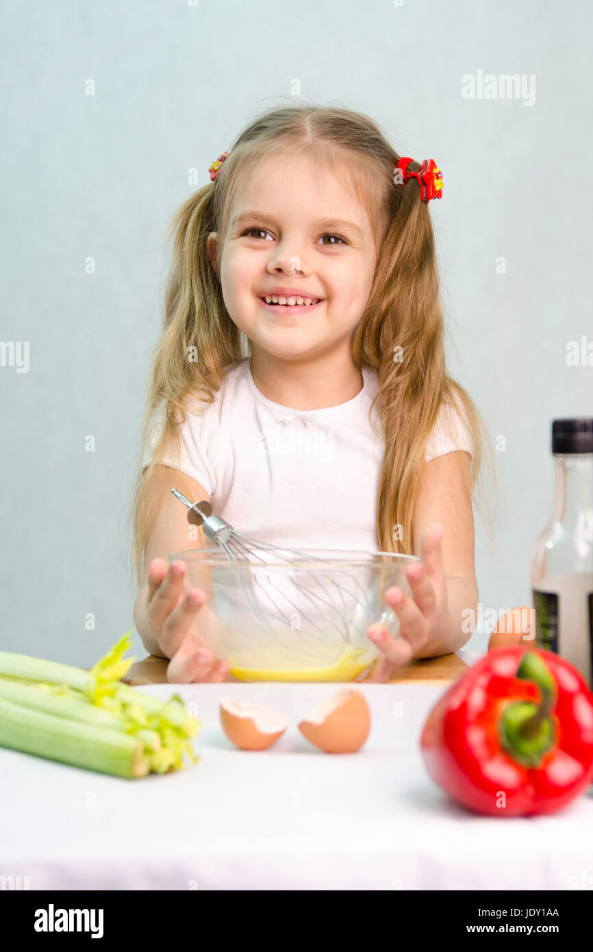 Girl playing in a cook. Girl churn whisk the eggs in a glass bowl. At ...