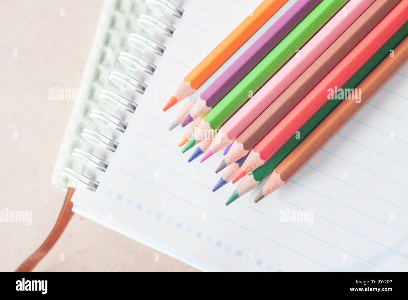 Top view of colorful pencil crayons on spiral notebook and green ...