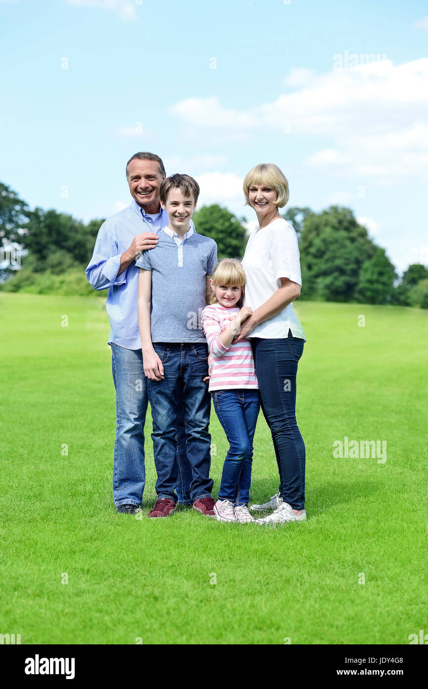 Happy family of four standing together on the meadow Stock Photo - Alamy