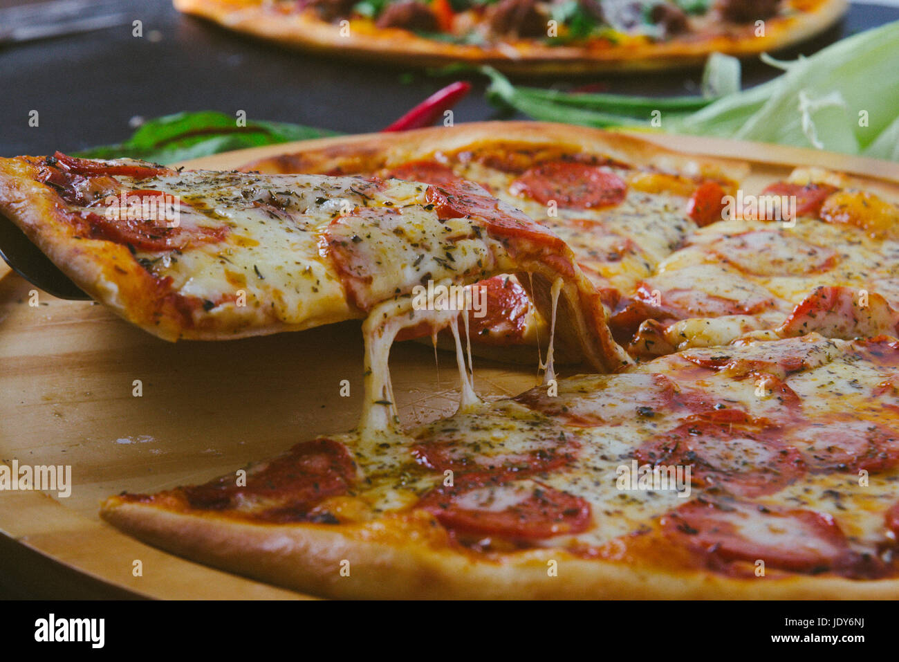 Hot pizza slice with melting cheese on a rustic dark wooden table Stock ...